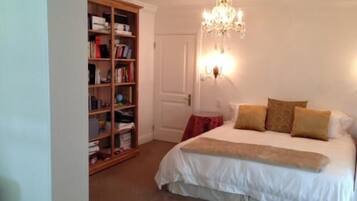 Quarto com uma cama grande, uma estante de madeira e um candelabro.