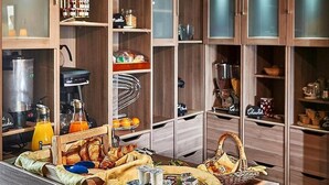Uma cozinha com armários de madeira, cafeteira e diversos utensílios.