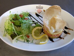 Um prato com sanduíche, salada e fatias de limão.
