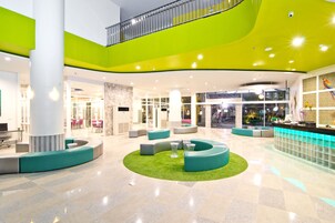 Um hall amplo com área de estar central, escada e balcão de recepção.