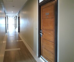 Corredor com porta de madeira com a inscrição 506, piso claro e teto com iluminação embutida.