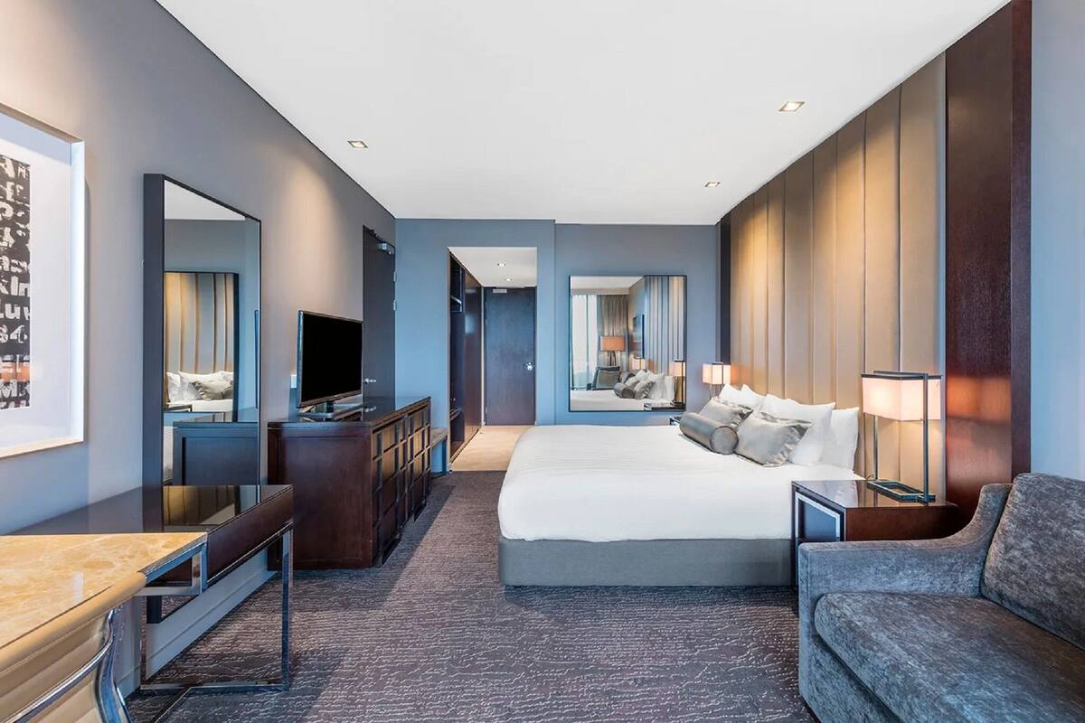Quarto de hotel moderno com uma cama grande, uma escrivaninha, televisão e área de estar.
