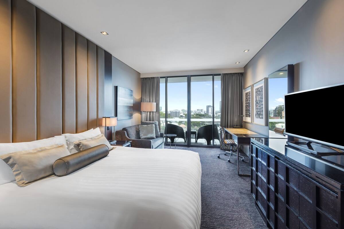 Quarto de hotel moderno com uma cama grande, uma escrivaninha e uma televisão.