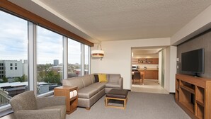Uma sala de estar moderna com um amplo sofá modular, uma mesinha e uma TV sobre um suporte de madeira.