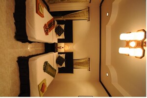 Quarto de hotel com cama, mesas de cabeceira, luminária na parede e cortina.