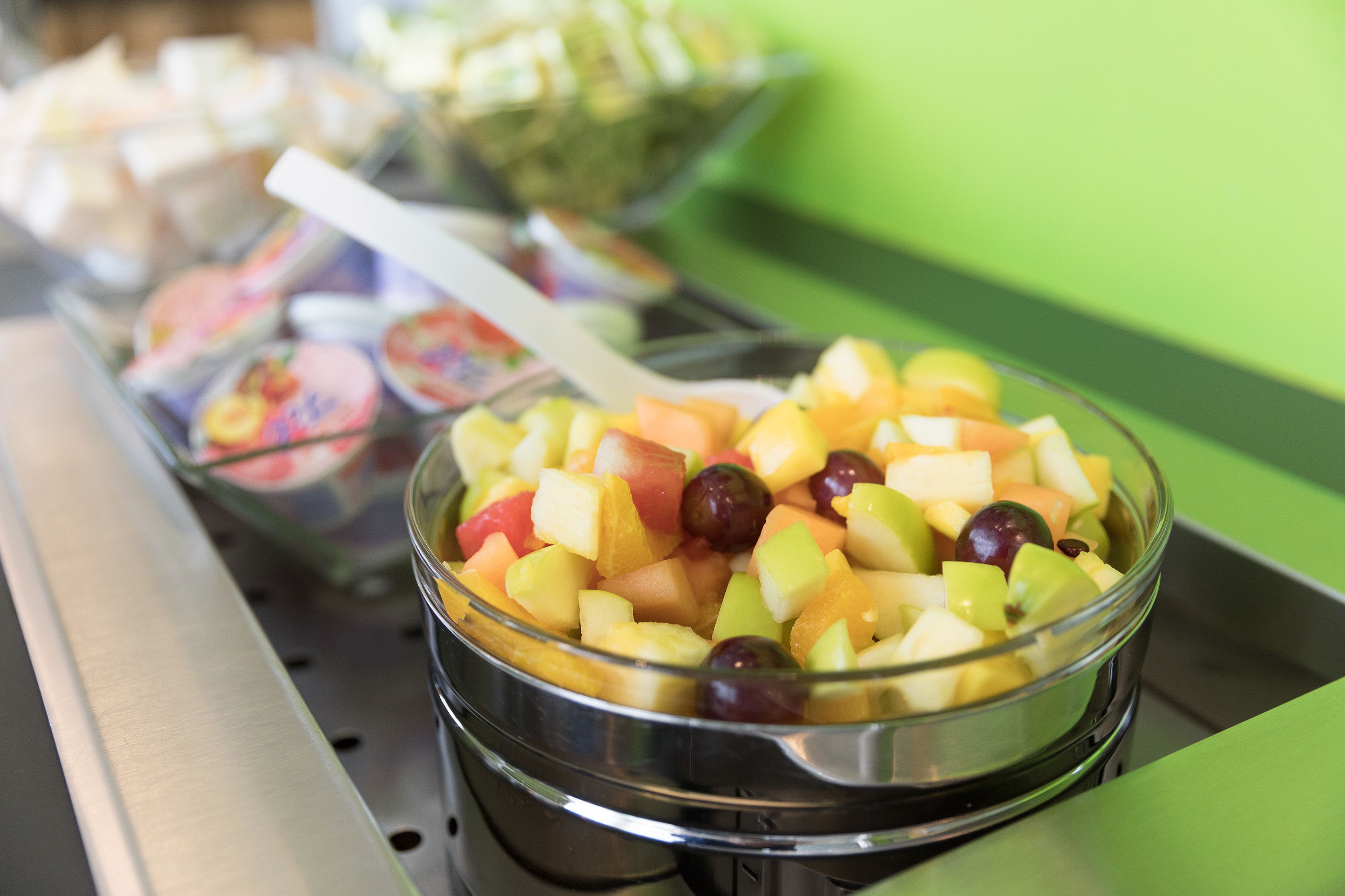Buffet com variedade de frutas e uma tigela de salada de frutas.