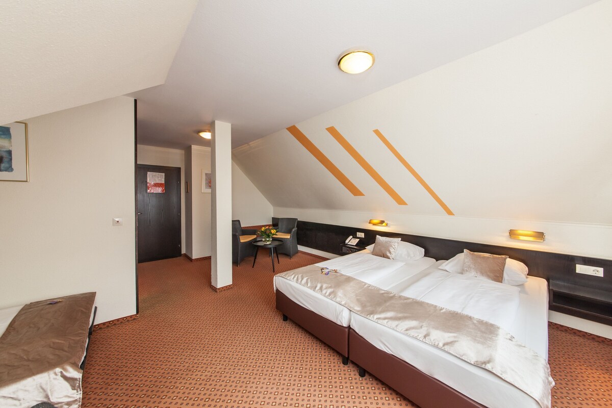 Quarto de hotel com uma cama grande, uma mesa e uma cadeira.