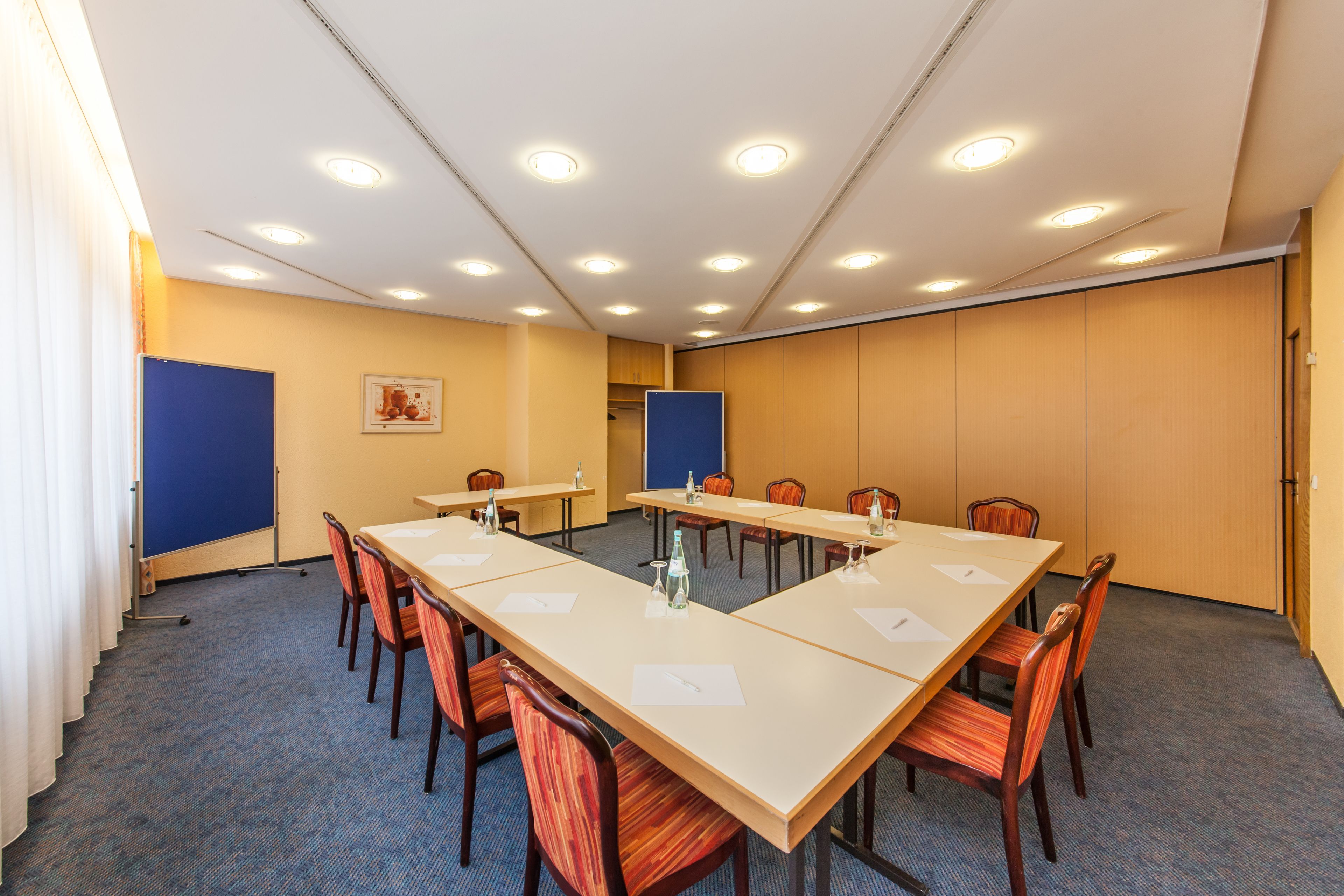 Uma sala de conferência com uma mesa comprida, cadeiras e um quadro branco.