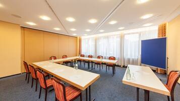 Sala de conferência com uma mesa comprida, várias cadeiras e um fundo azul.