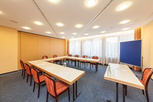 Sala de conferência com uma mesa comprida, várias cadeiras e um fundo azul.