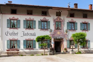 Um edifício com várias janelas, um banco e uma placa com a inscrição 'Balthot Jachernau'.