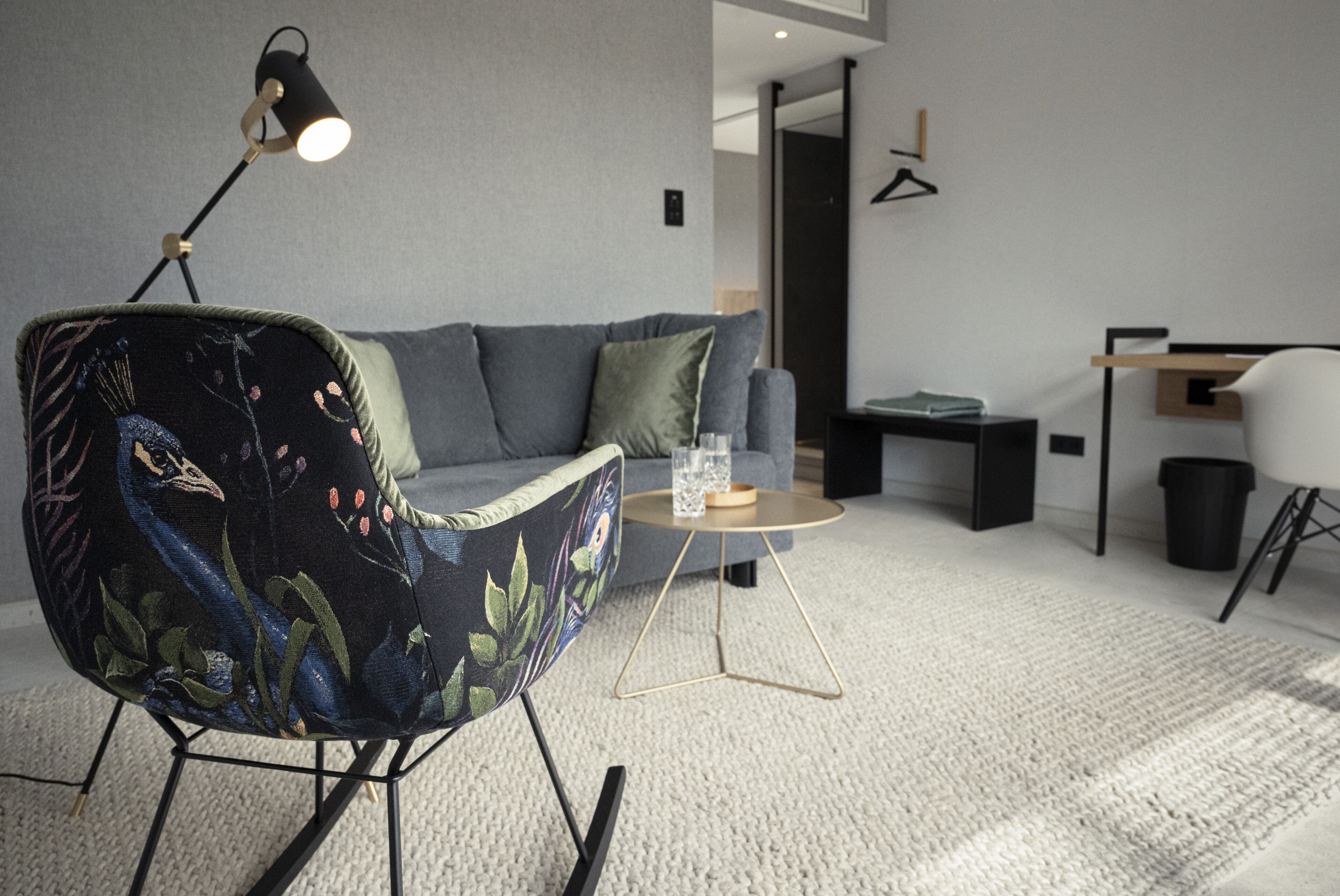 Uma sala de estar moderna com um sofá, uma mesa de centro redonda, um abajur e uma pequena mesa lateral.