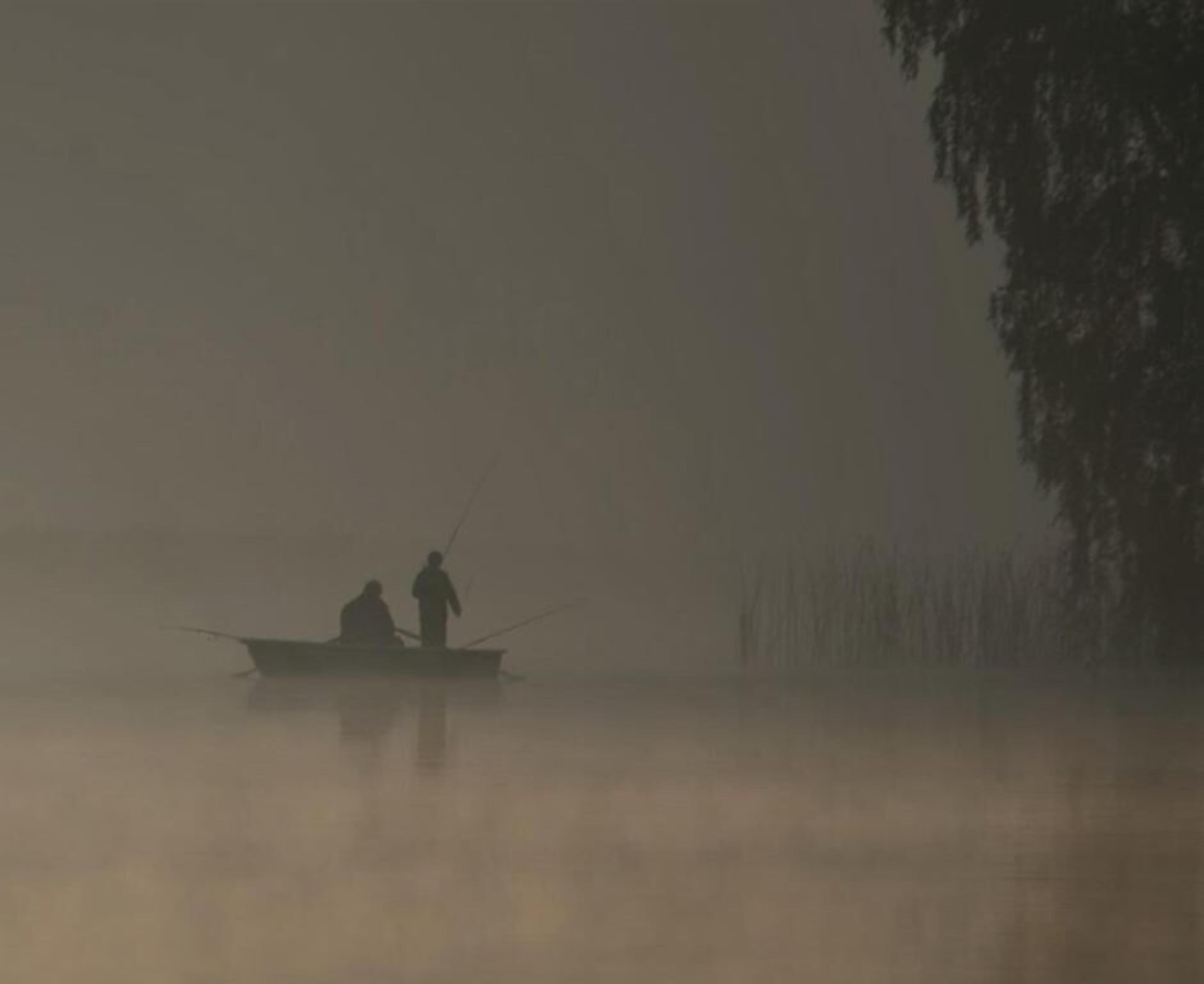 Um barco com duas pessoas num lago nevoento.