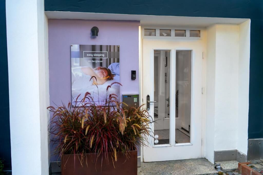 Entrada de hotel com porta, cartaz anunciando 'easy sleeping' e planta em vaso.