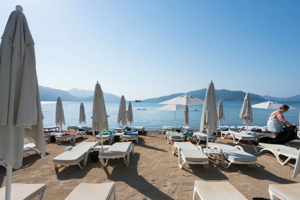 Praia particular, espreguiçadeiras, guarda-sóis, toalhas de praia