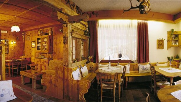 Um quarto acolhedor de madeira com área de refeições, um sofá e uma janela com cortinas.