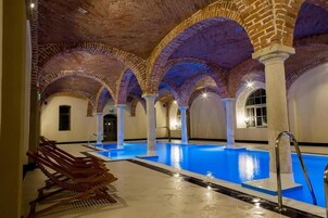 Piscina interior com teto abobadado em tijolo e colunas brancas.