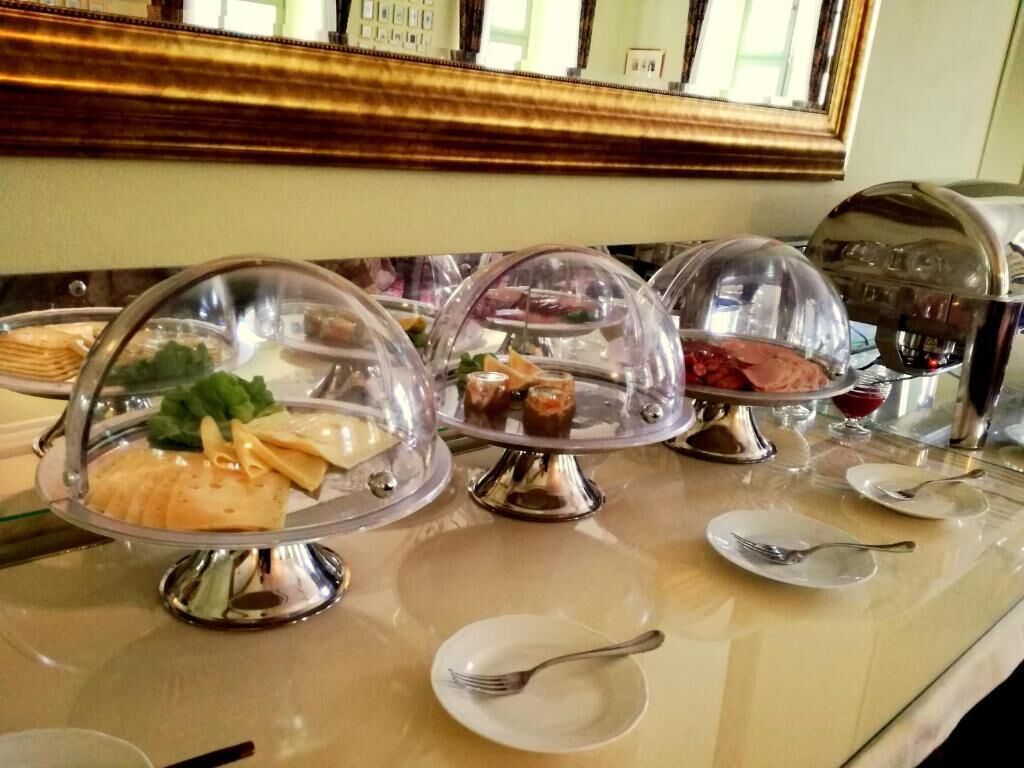 Disposição de buffet com diversos alimentos sob cúpulas de vidro em uma bancada de mármore.