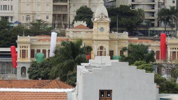 Um edifício histórico com torre do relógio, cercado por edifícios modernos e palmeiras.