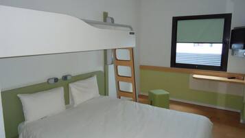 Uma cama beliche com escada, um banquinho, uma televisão e uma janela com persianas.