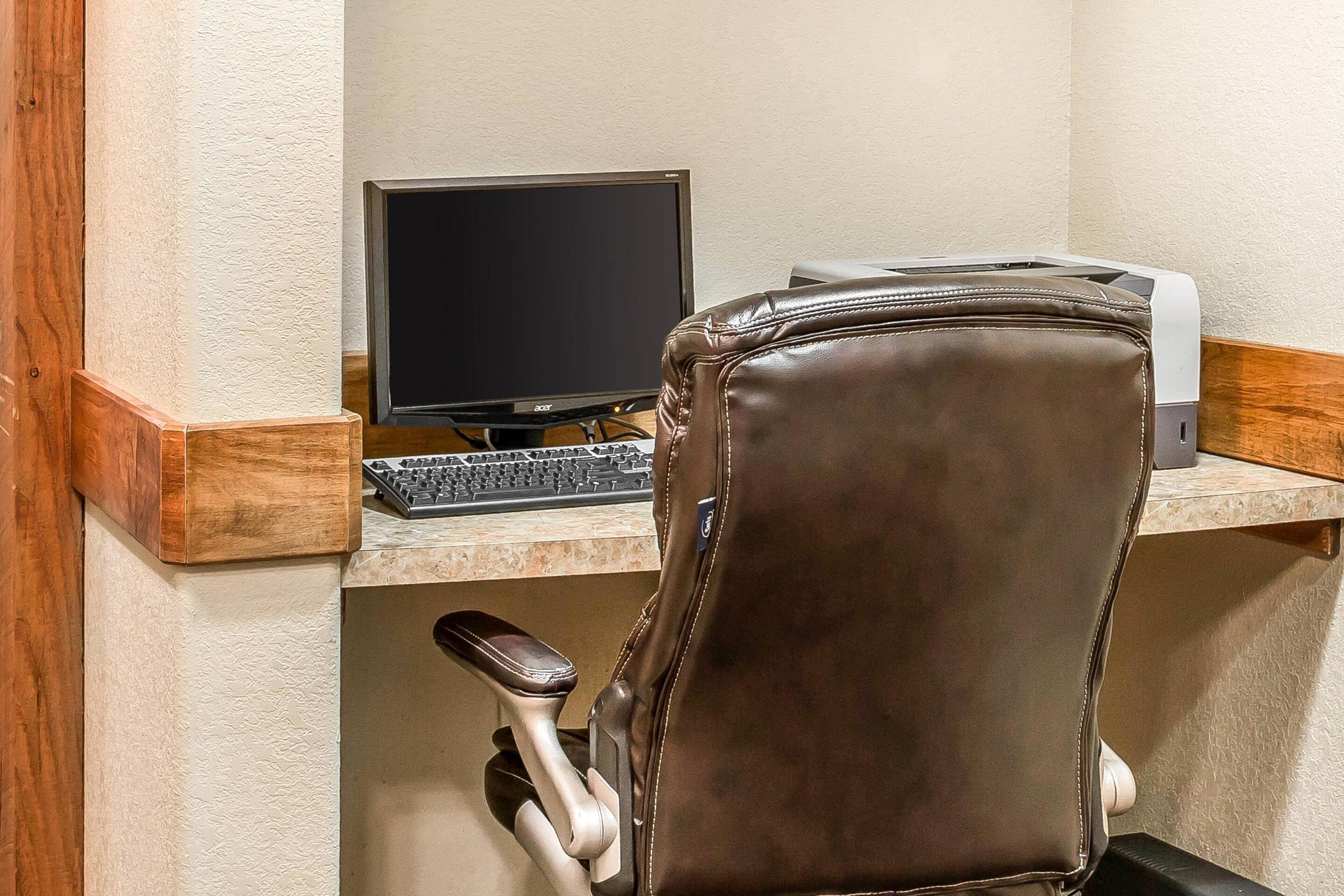 Um espaço de trabalho com computador, teclado e cadeira de couro.