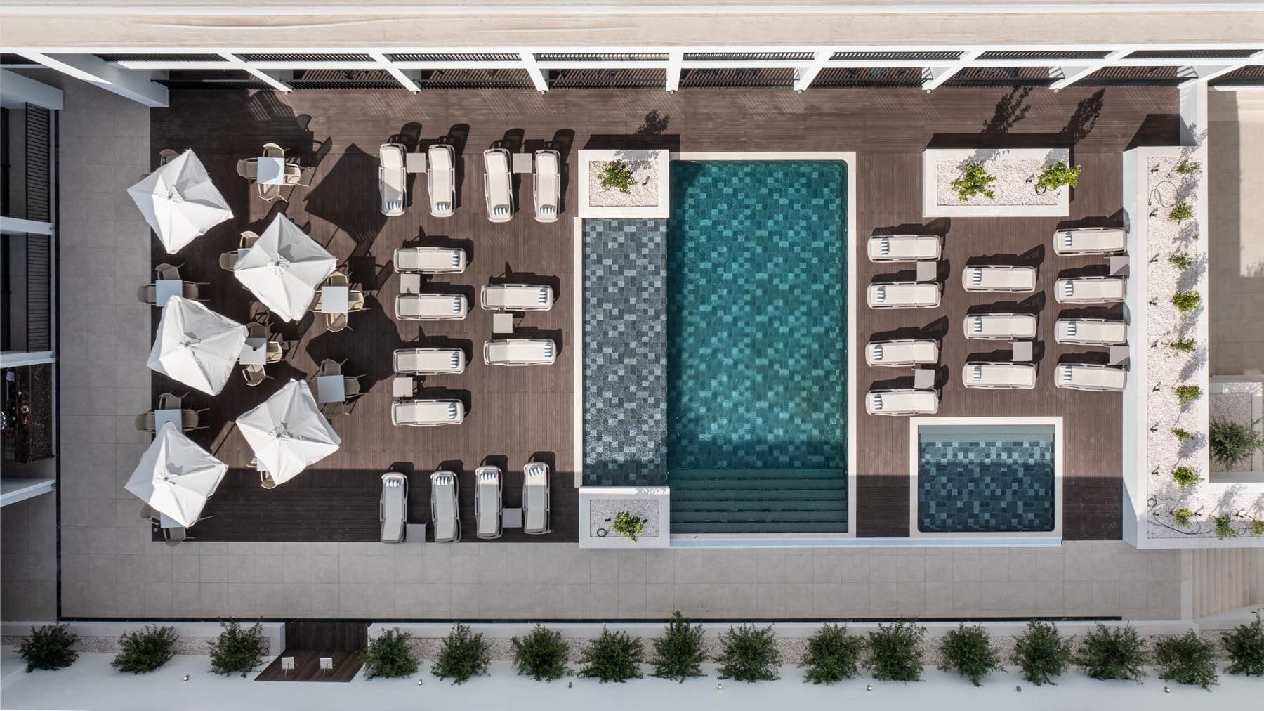 Área de piscina no terraço com espreguiçadeiras, guarda-sóis e um espaço para sentar.