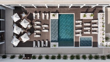 Área de piscina no terraço com espreguiçadeiras, guarda-sóis e um espaço para sentar.