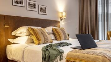 Quarto de hotel com cama, um laptop e três quadros na parede.