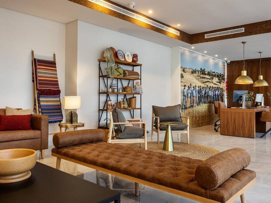 Uma sala de estar moderna com um sofá, poltronas, uma mesa de centro e uma estante.