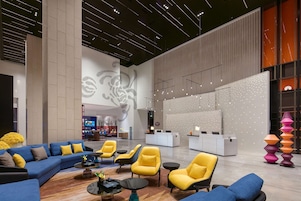 Um hall amplo com balcão de recepção, área de estar e iluminação decorativa.