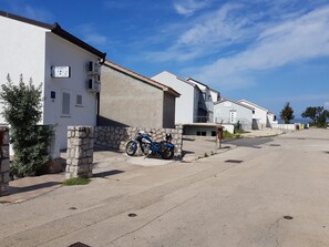 Uma área residencial com uma fileira de edifícios brancos, um muro de pedra e uma motocicleta azul estacionada na frente.