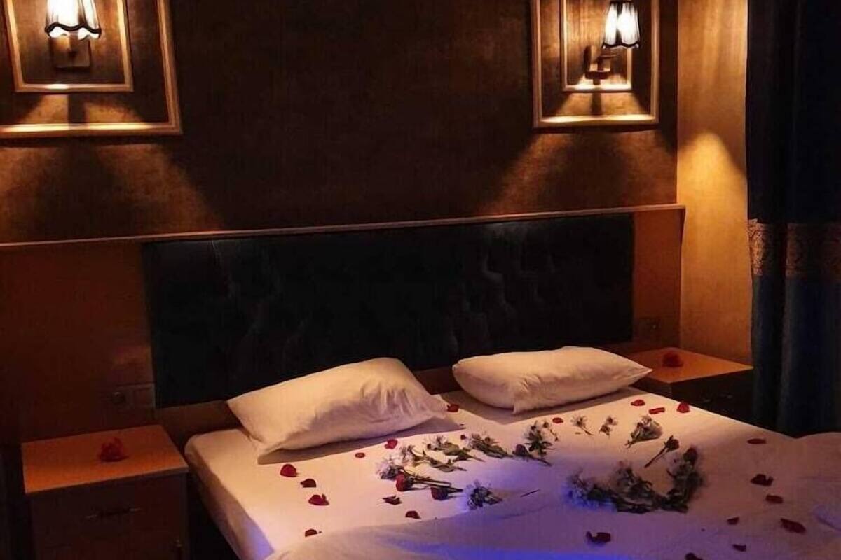 Quarto de hotel com uma cama grande, duas mesas de cabeceira e iluminação embutida na parede.
