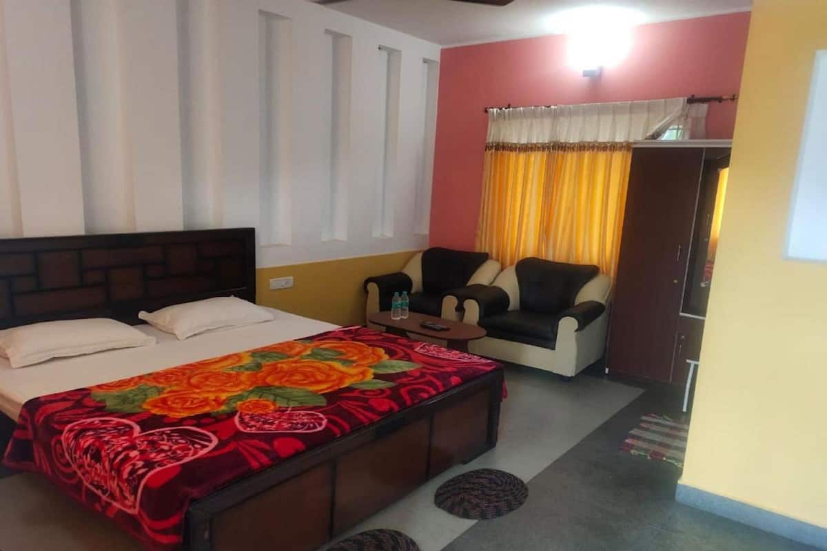 Um quarto com uma cama, uma cadeira, uma mesinha e um guarda-roupa.