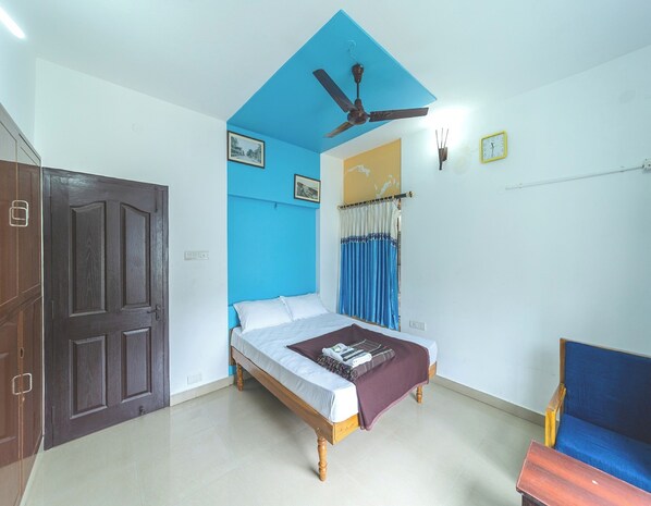 Quarto com cama, ventilador de teto, janela com cortinas e porta.