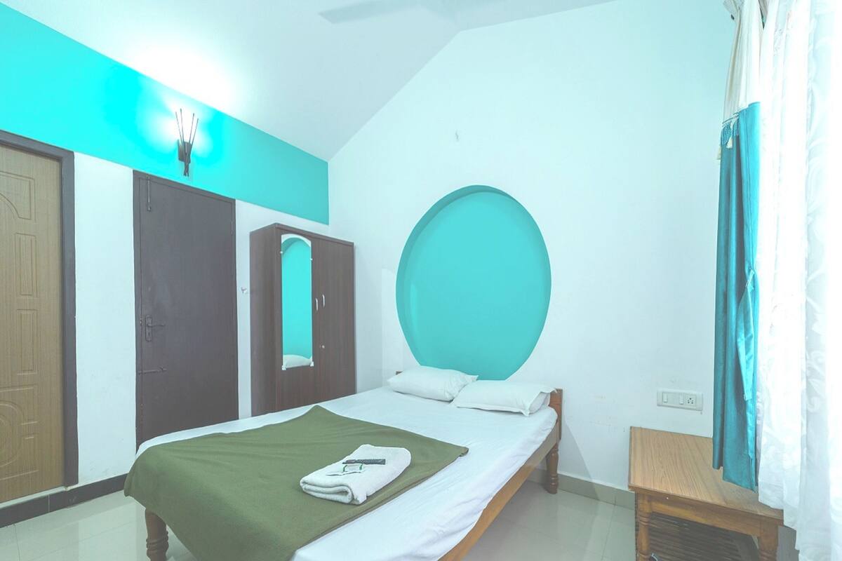 Quarto com cama, guarda-roupa, espelho e um elemento decorativo circular na parede.