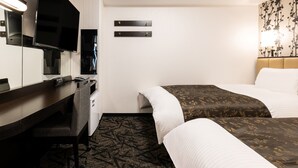 Quarto de hotel com secretária, duas camas, televisão de tela plana e televisão montada na parede.