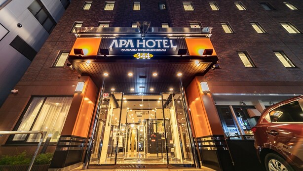 Entrada do APA HOTEL com design moderno, destacando uma placa e porta de vidro.