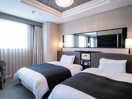 Quarto de hotel com duas camas, um espelho grande, uma televisão de tela plana e um painel de controle.