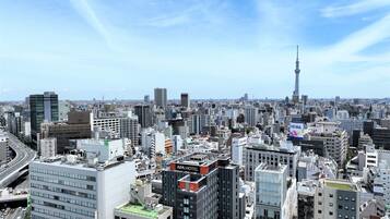 Paisagem urbana com um hotel em destaque, chamado 'APA HOTEL', e uma torre ao longe.