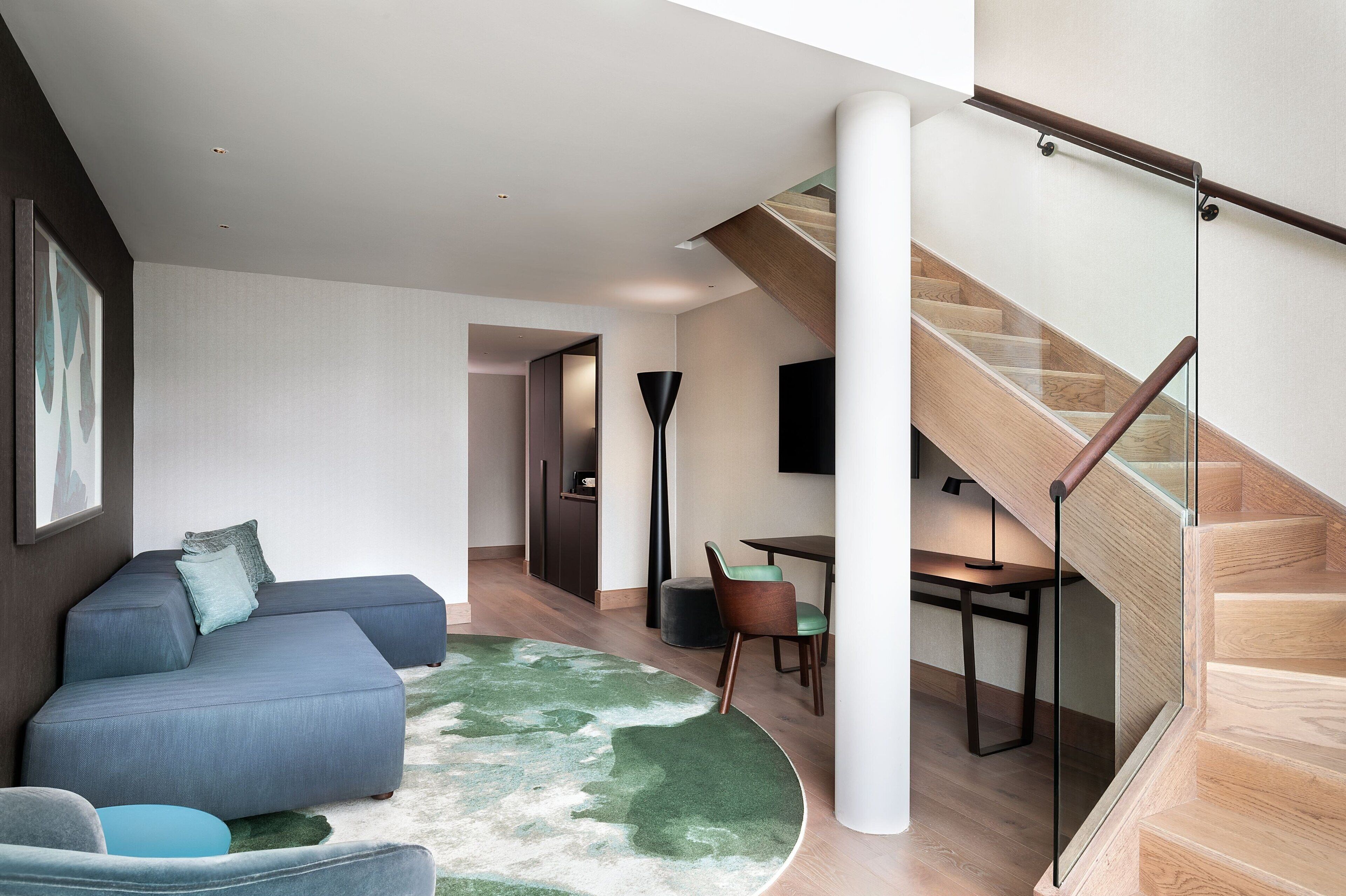 Uma sala de estar moderna com um sofá modular, uma área de refeições e uma escada.