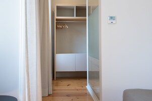 Um closet espaçoso com piso de madeira, uma barra para pendurar roupas e uma prateleira embutida.