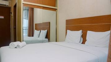Quarto de hotel com uma cama grande, cabeceira de madeira e um espelho refletindo o ambiente.
