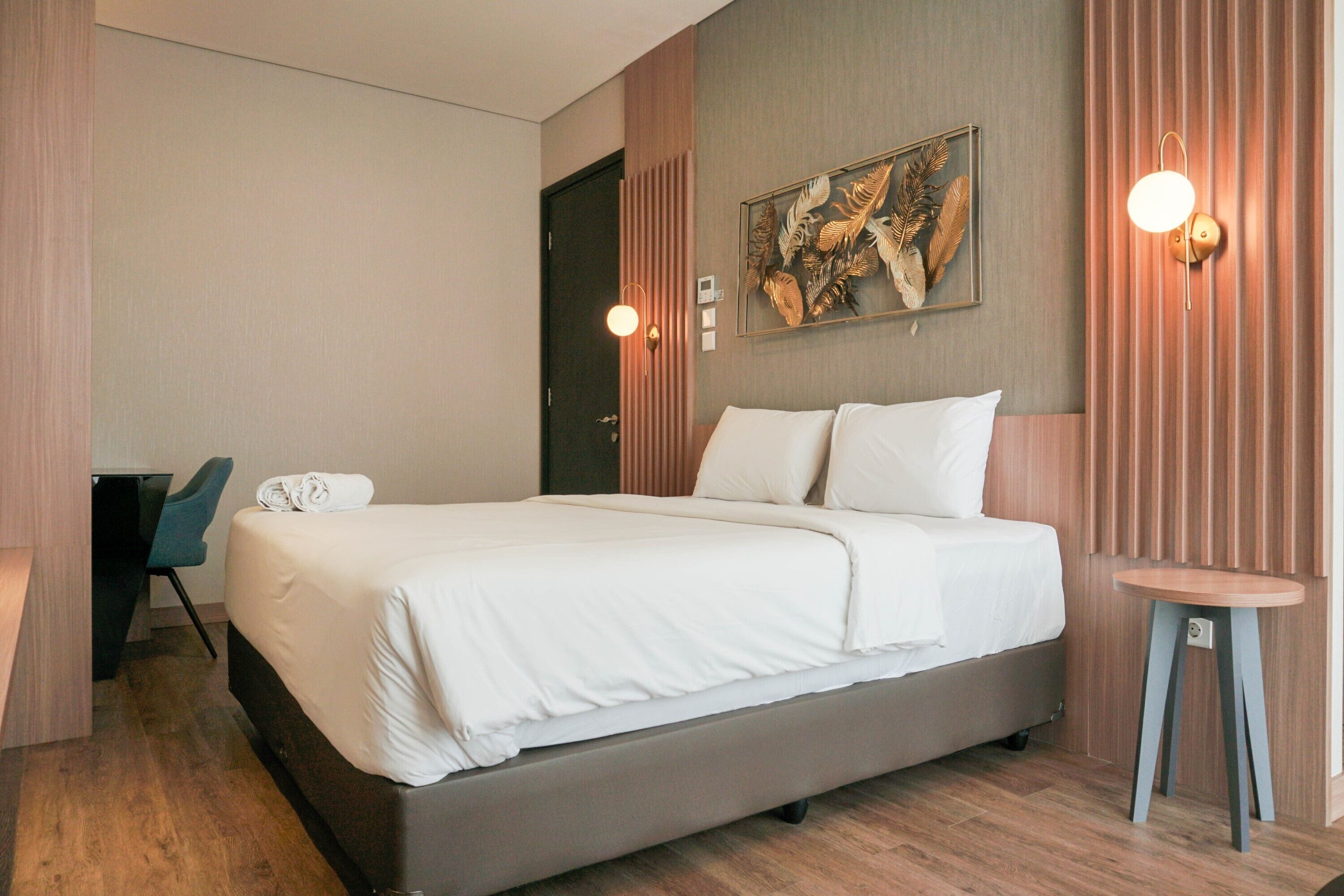 Quarto de hotel moderno com uma cama grande, uma mesa e uma cadeira.