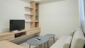 Uma sala de estar moderna com televisão de tela plana, estantes de madeira, um sofá e duas mesinhas.