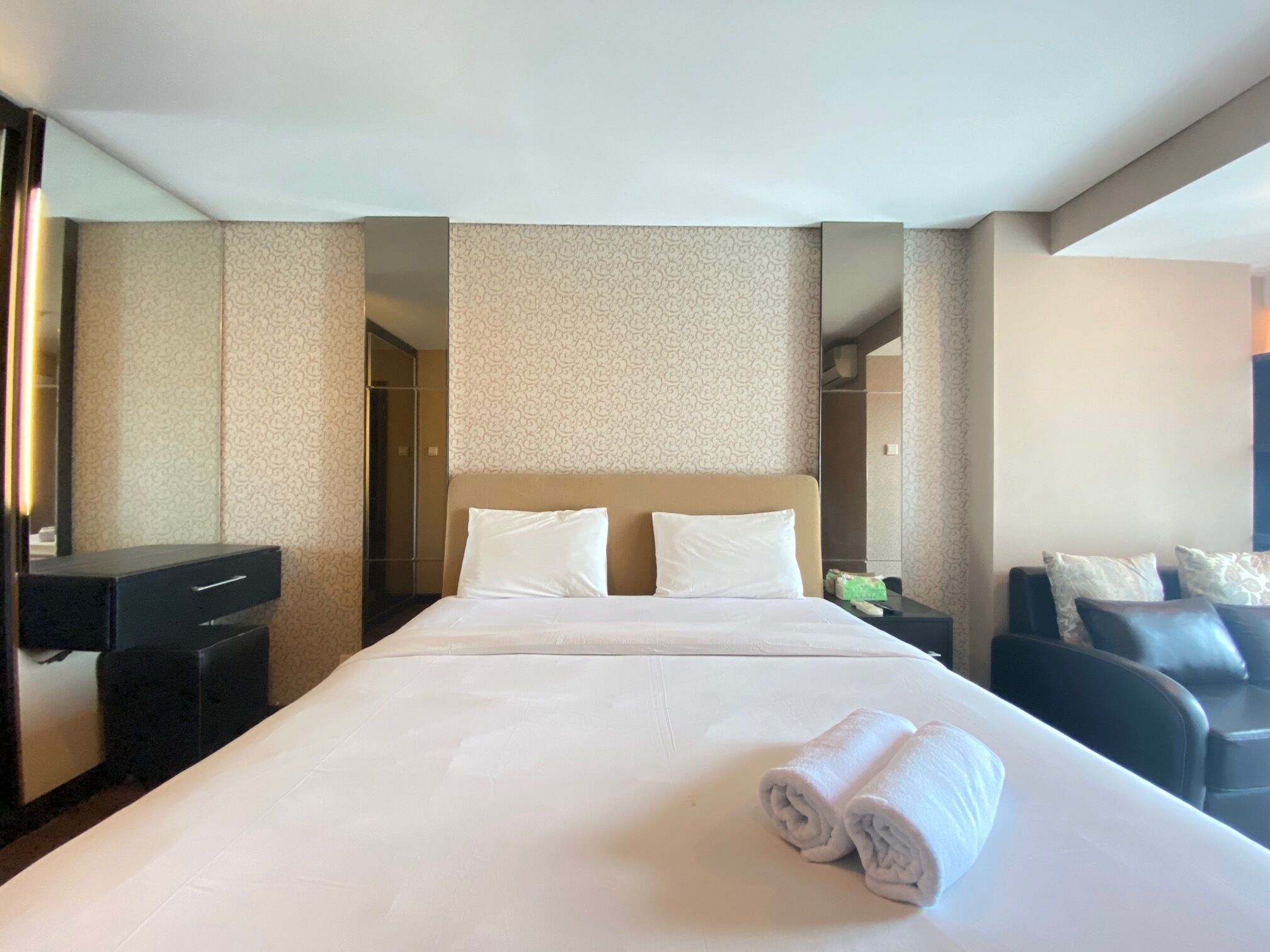 Quarto de hotel com uma cama grande, duas mesas de cabeceira, uma escrivaninha e uma cadeira.