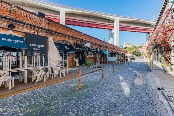 Uma rua de paralelepípedos com mesas ao ar livre e um edifício de tijolos.