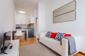 Uma sala de estar moderna com um sofá branco, uma televisão e um controle remoto sobre uma mesa.