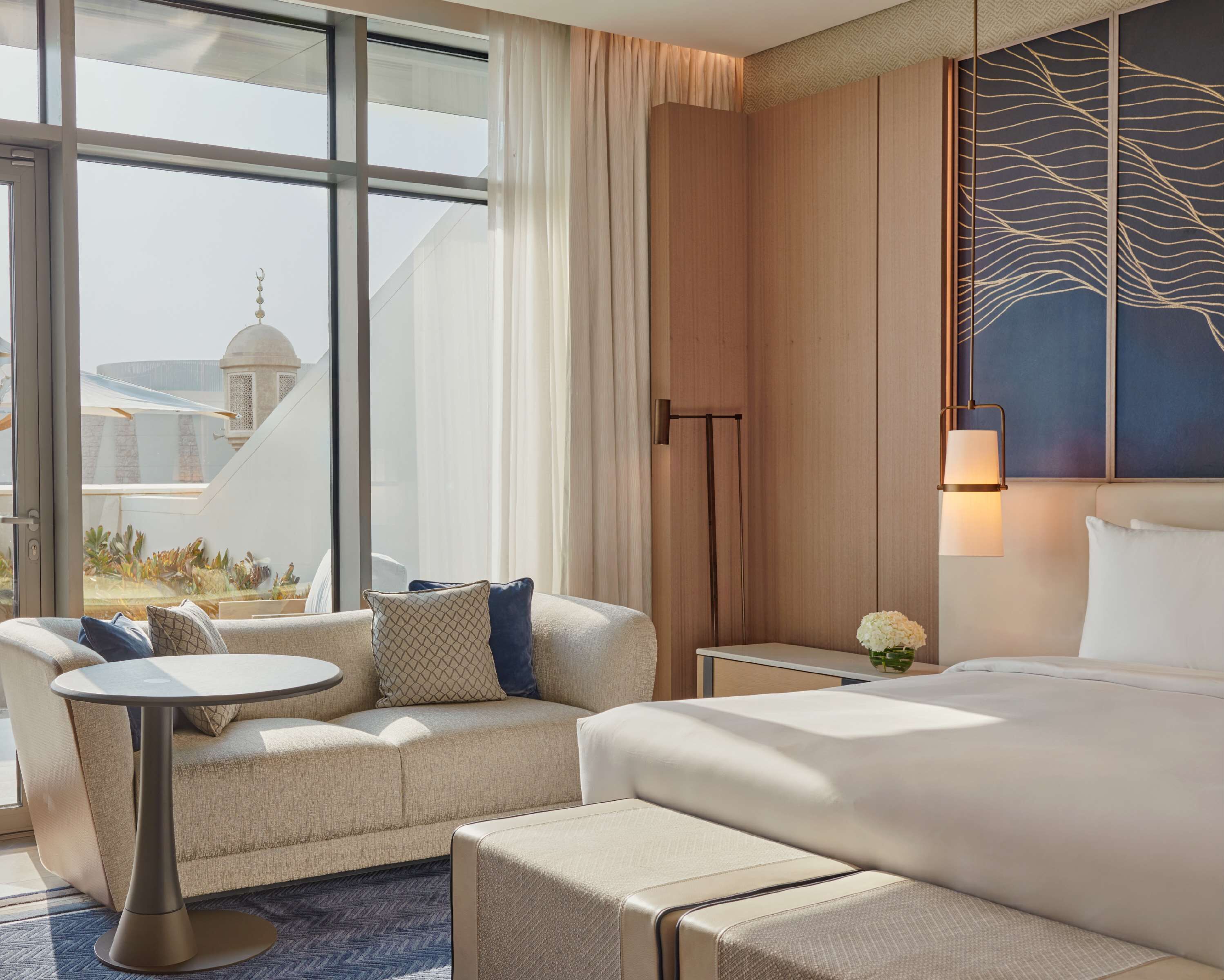 Quarto de hotel com uma cama, um sofá, uma mesinha e vista para um edifício com cúpula.