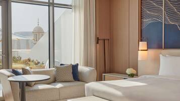 Quarto de hotel com uma cama, um sofá, uma mesinha e vista para um edifício com cúpula.