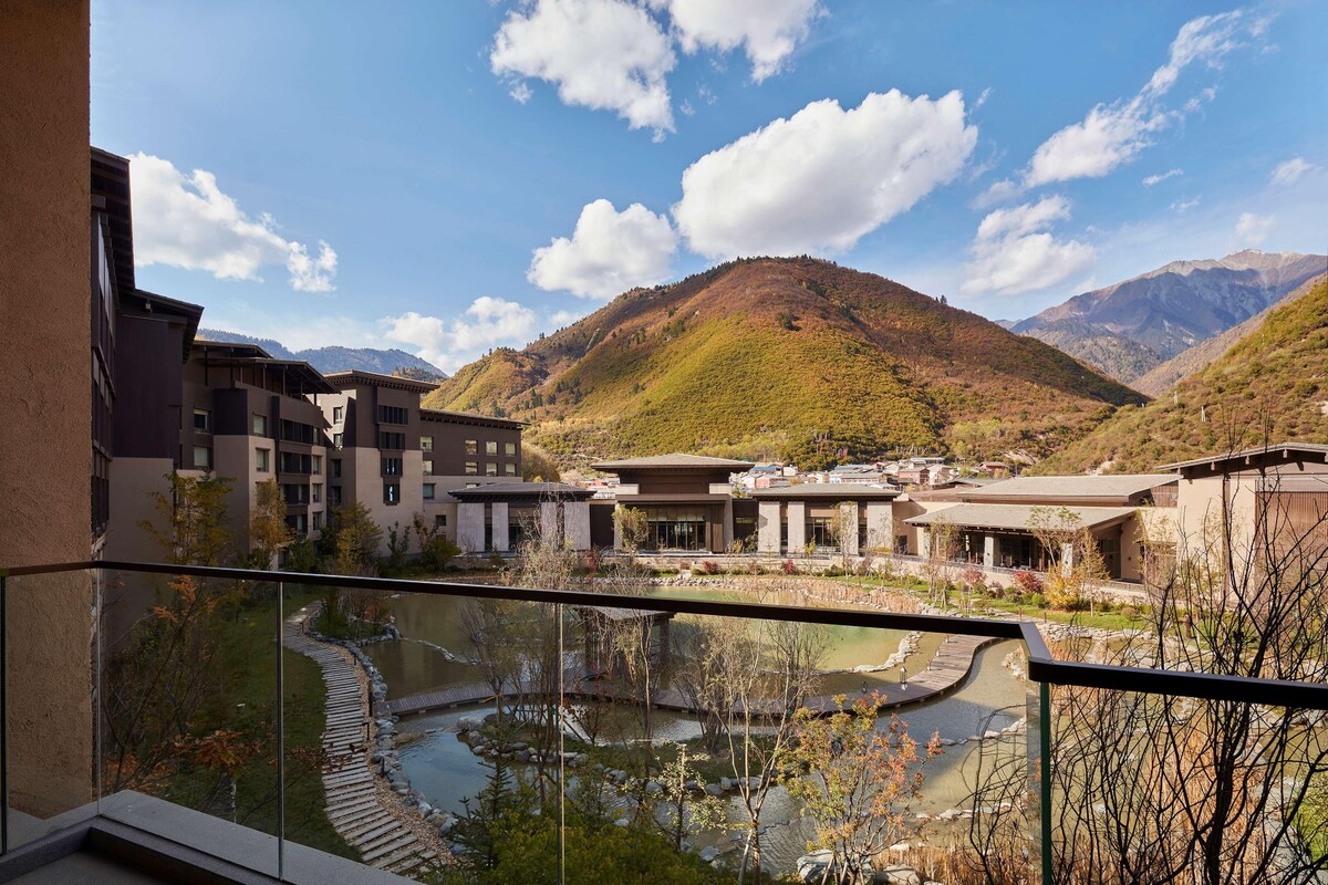 Hotel com vista para uma montanha, um lago e um céu limpo.